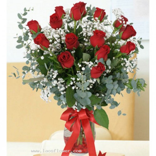 15 long-stemmed red roses in a vase accent with white gypsophila.